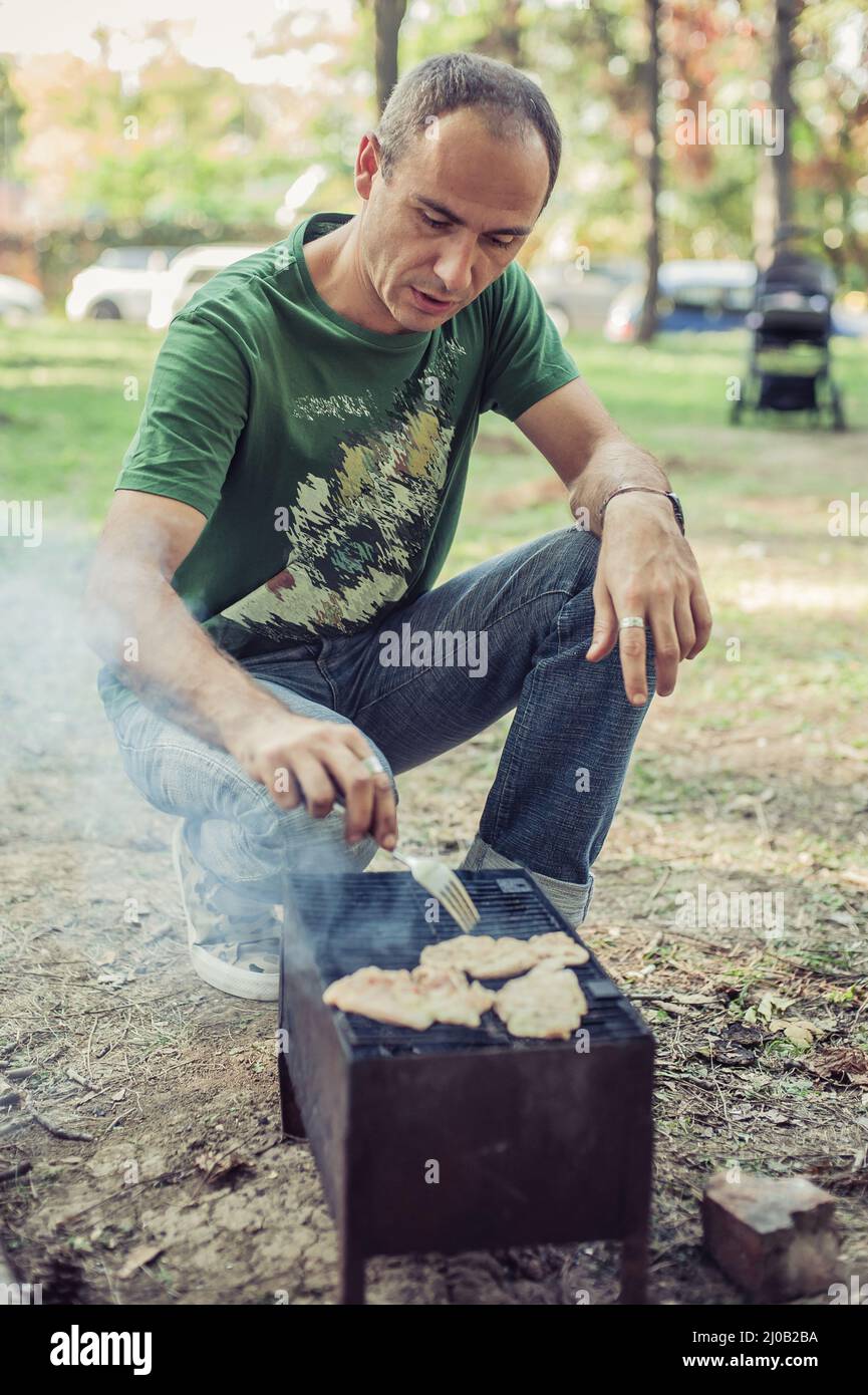 Hungry man making barbecue outdoors in the park Stock Photo - Alamy