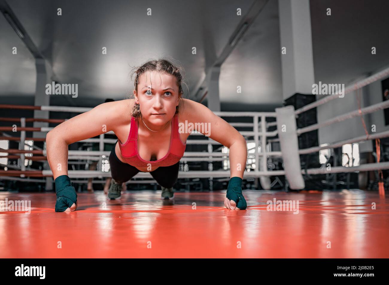 Young woman doing push-ups in the ring. Young athletic woman in ...