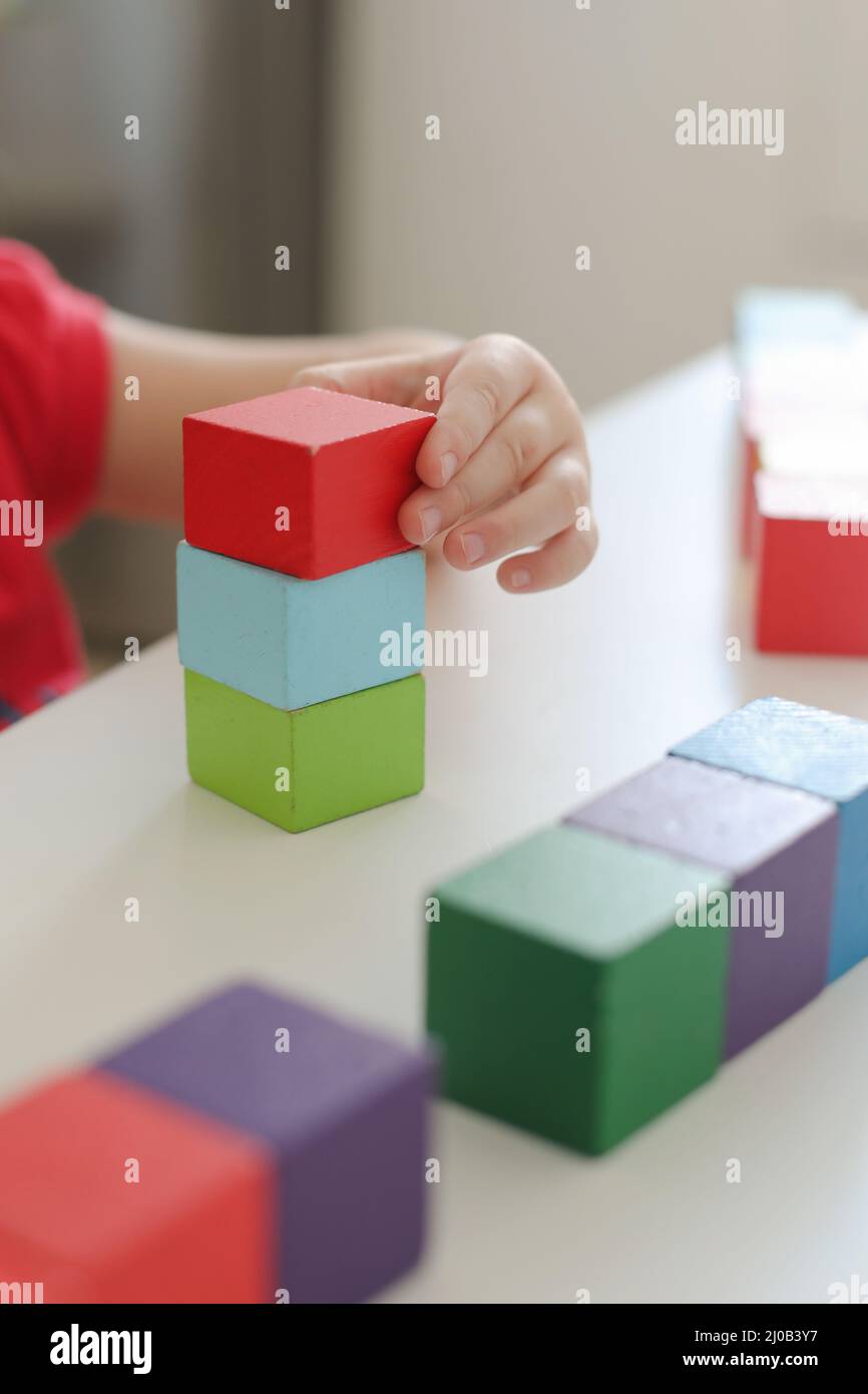 child playing and building with colorful wooden toy bricks on white ...