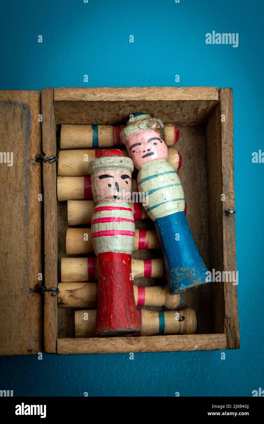 Vintage wooden sailor figurines stored in a wooden box against a blue ...