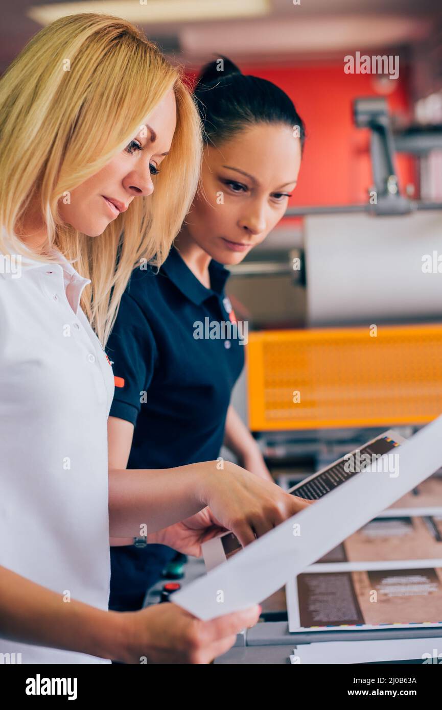 Two young woman working in printing factory. Printing Press Stock Photo ...