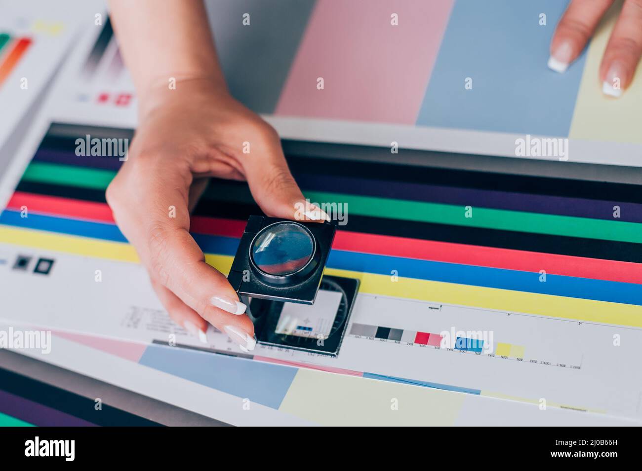 Worker in a printing and press centar uses a magnifying glass and check ...