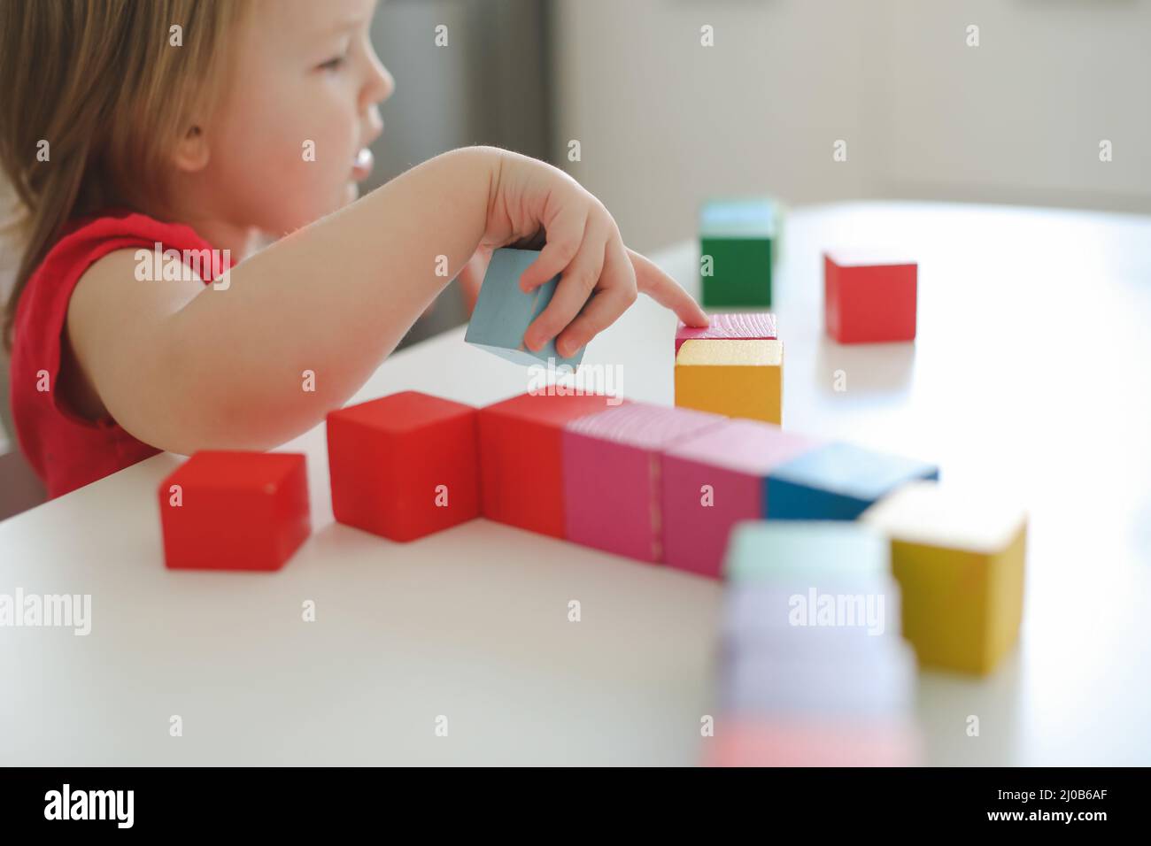 child playing and building with colorful wooden toy bricks on white ...