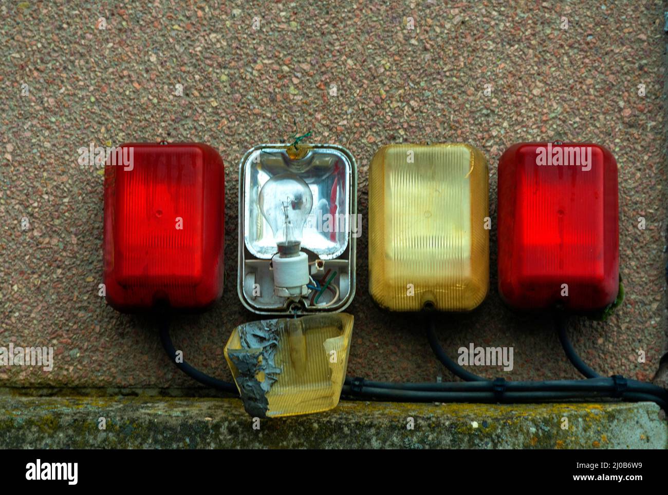 Various colored warning lights mounted on a wall with one damaged light ...
