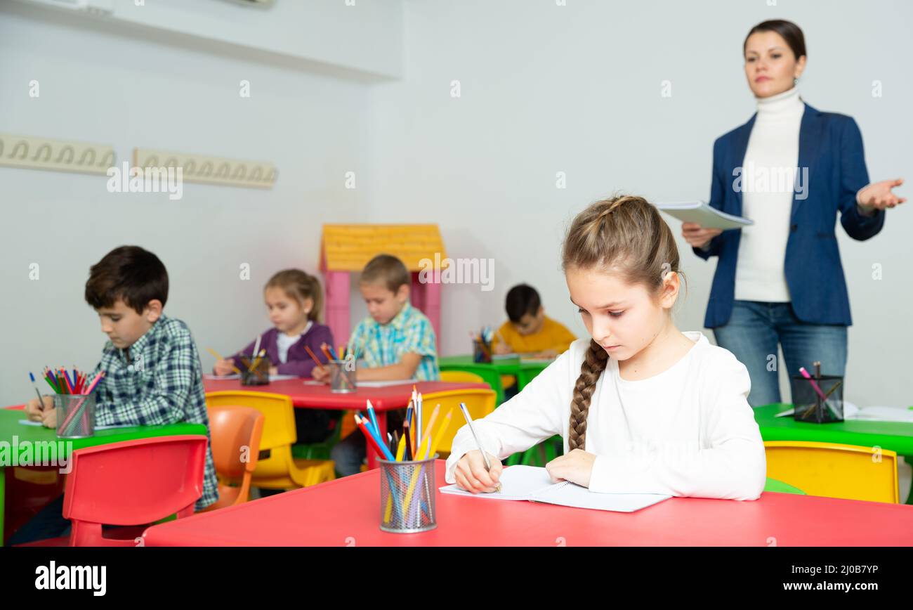 Friendly teacher woman helping girl during lesson in schoolroom Stock ...