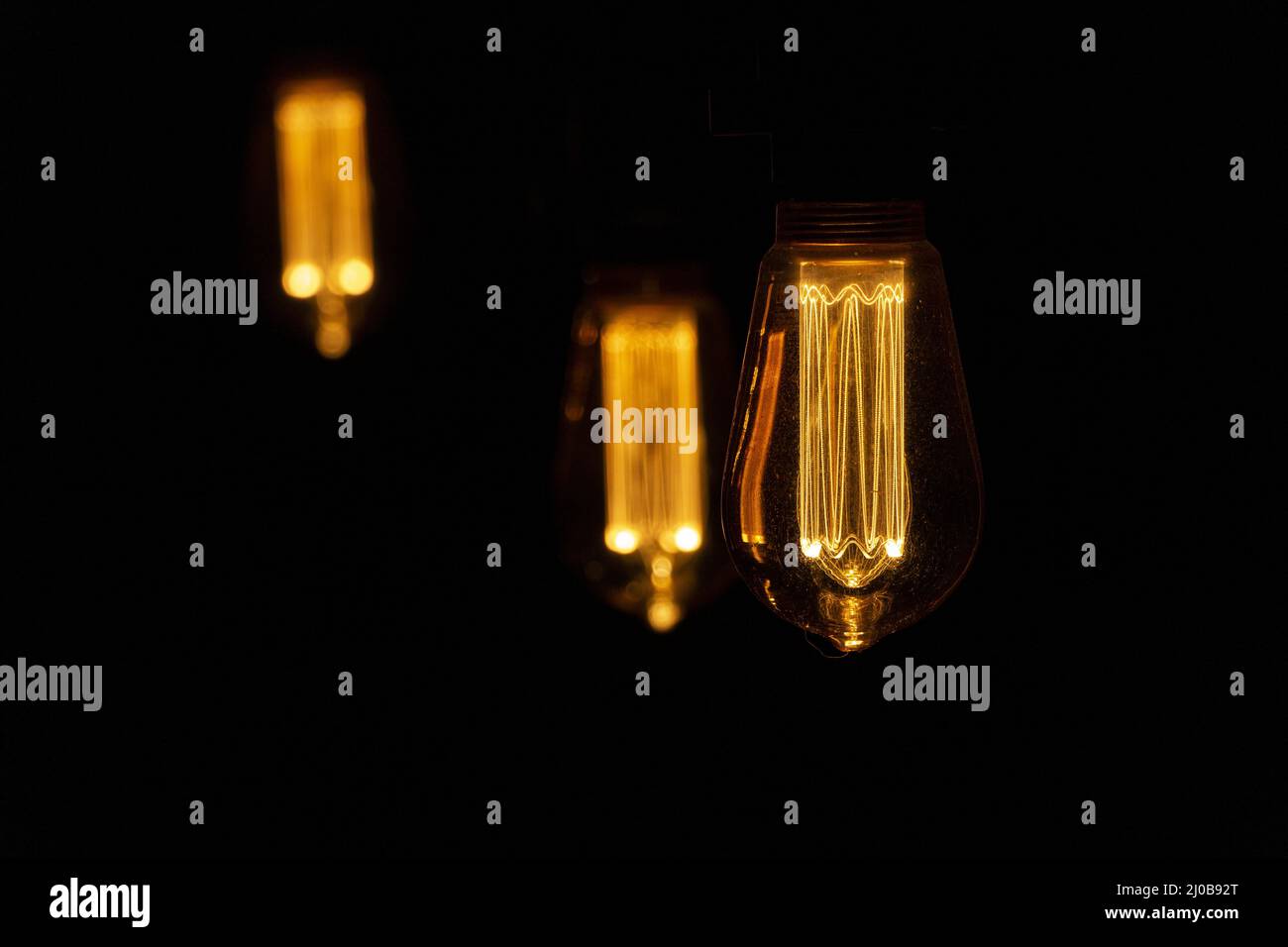 Eerie scenery of lightbulbs with golden lights in a black room Stock ...