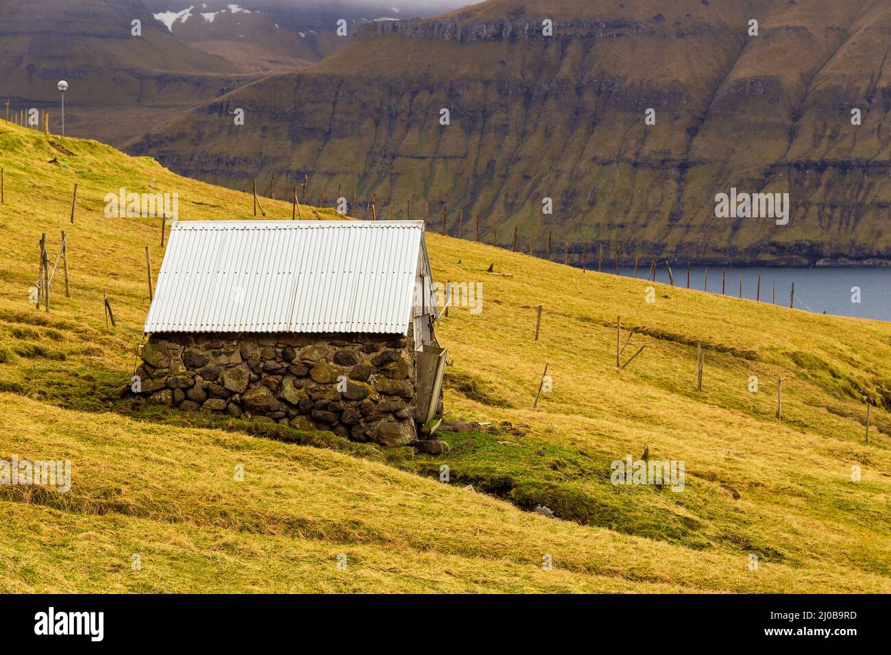 Stone building situated on the slope of the mountain on Eysturoy island ...