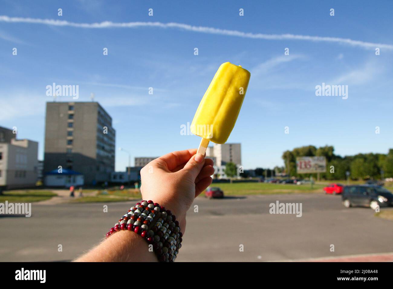 Yellow ice cream popsicle on a stick towards blue sky. High quality ...