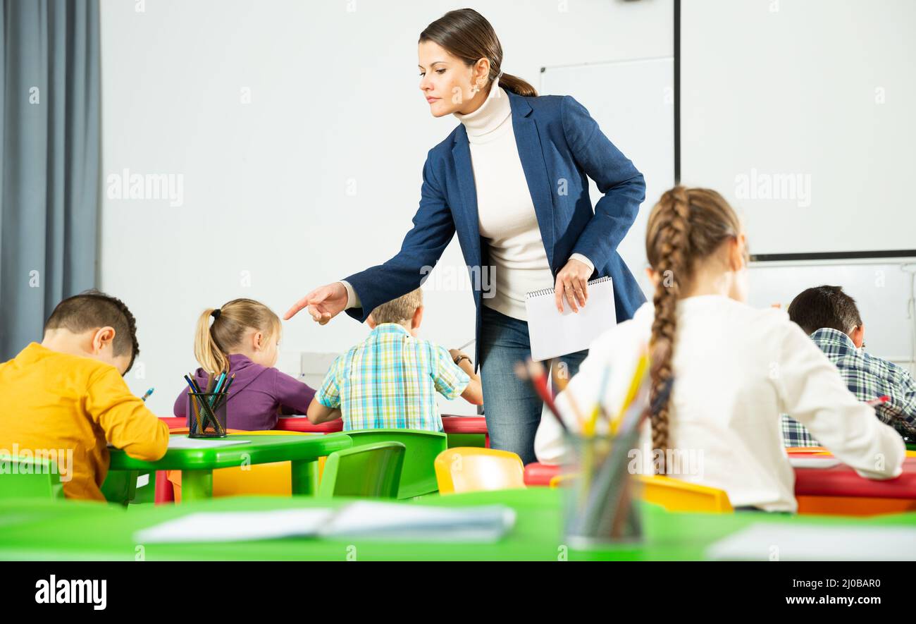 Teacher controlling writing of elementary school students Stock Photo ...