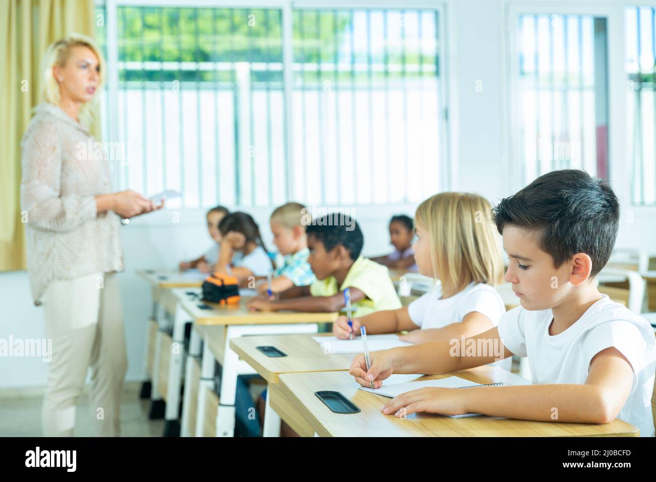 Focused preteen pupils studying in classroom with female teacher Stock ...
