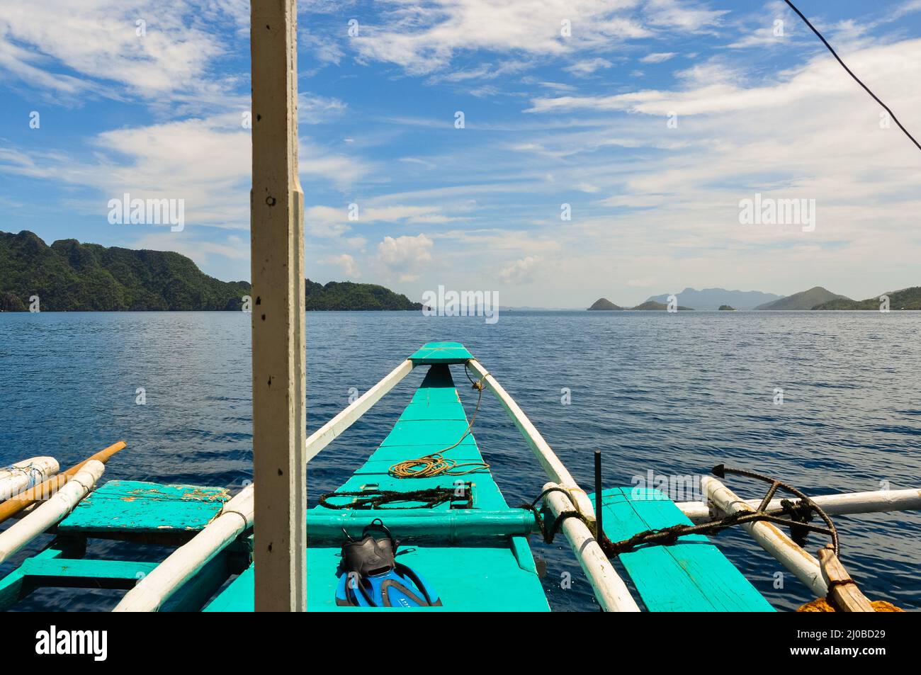 Tip of a wooden filipino Boat Facing the blue ocean and sky with clouds ...