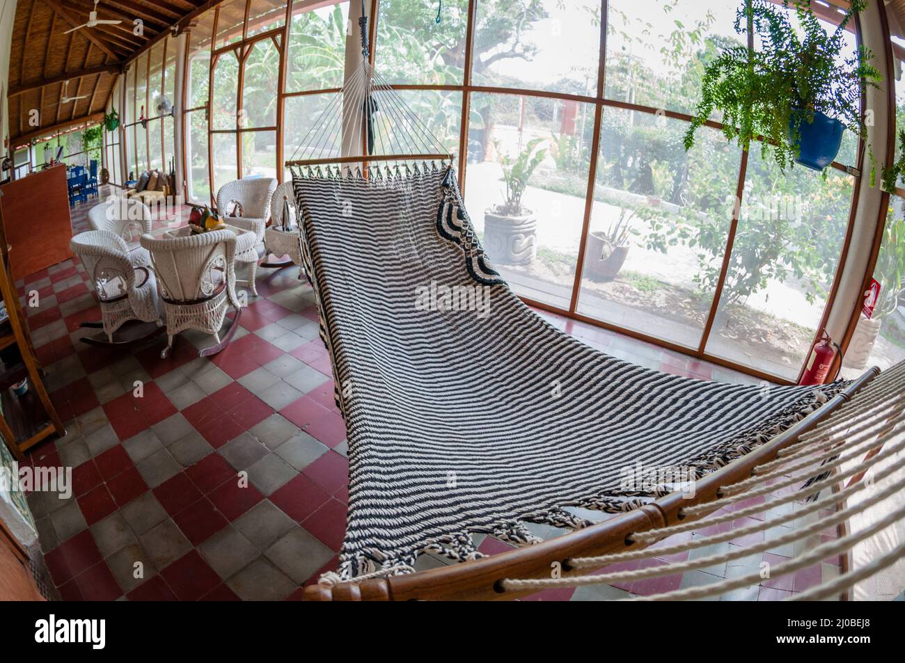 White huge hammock and rattan furniture on tiled floor in a hostel ...