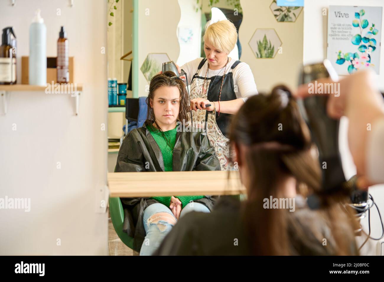 A woman in a hairdresser salon and the barber hairdressing her hair ...