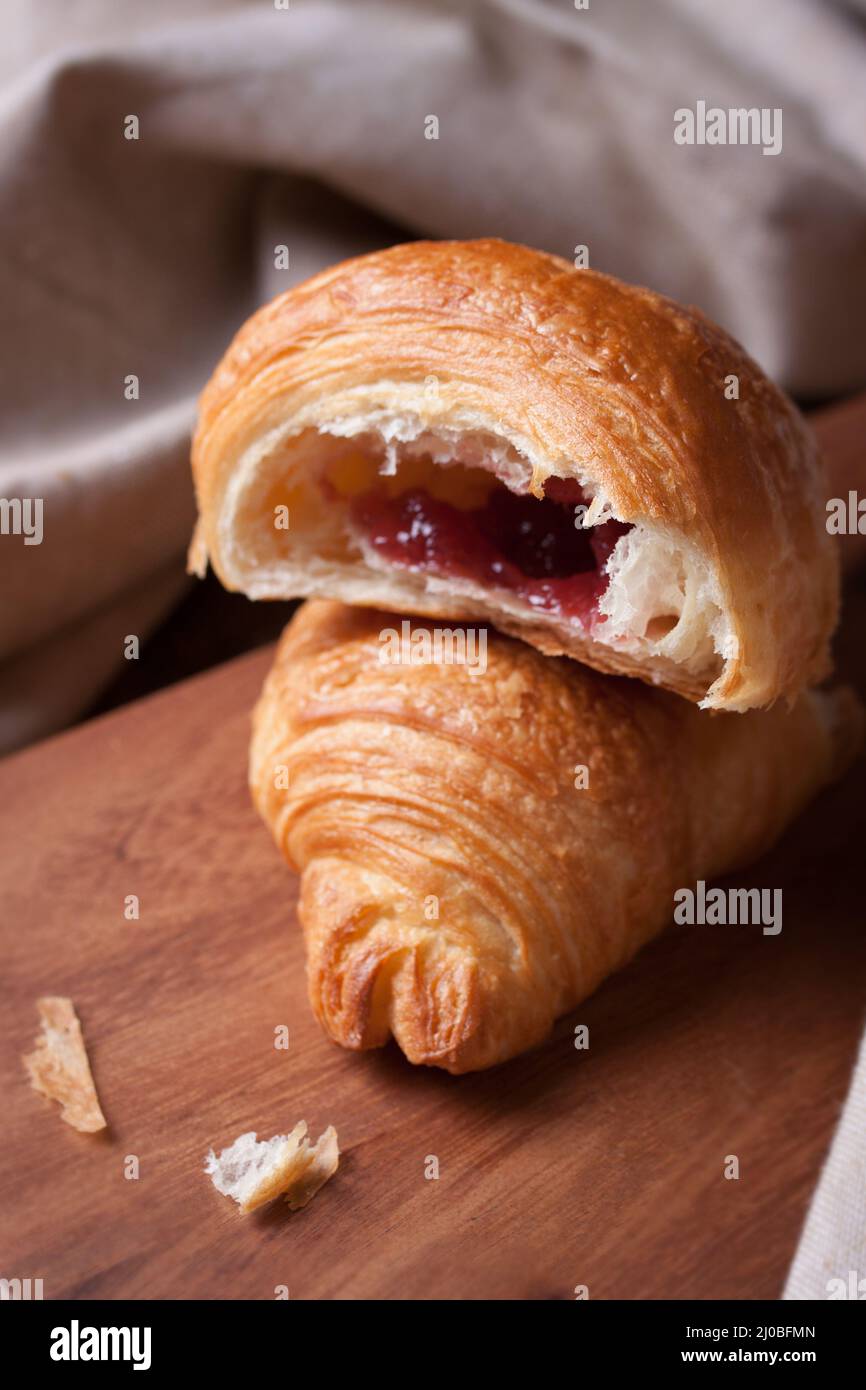 Closeup of croissant with jam on a wooden background. selective focus ...