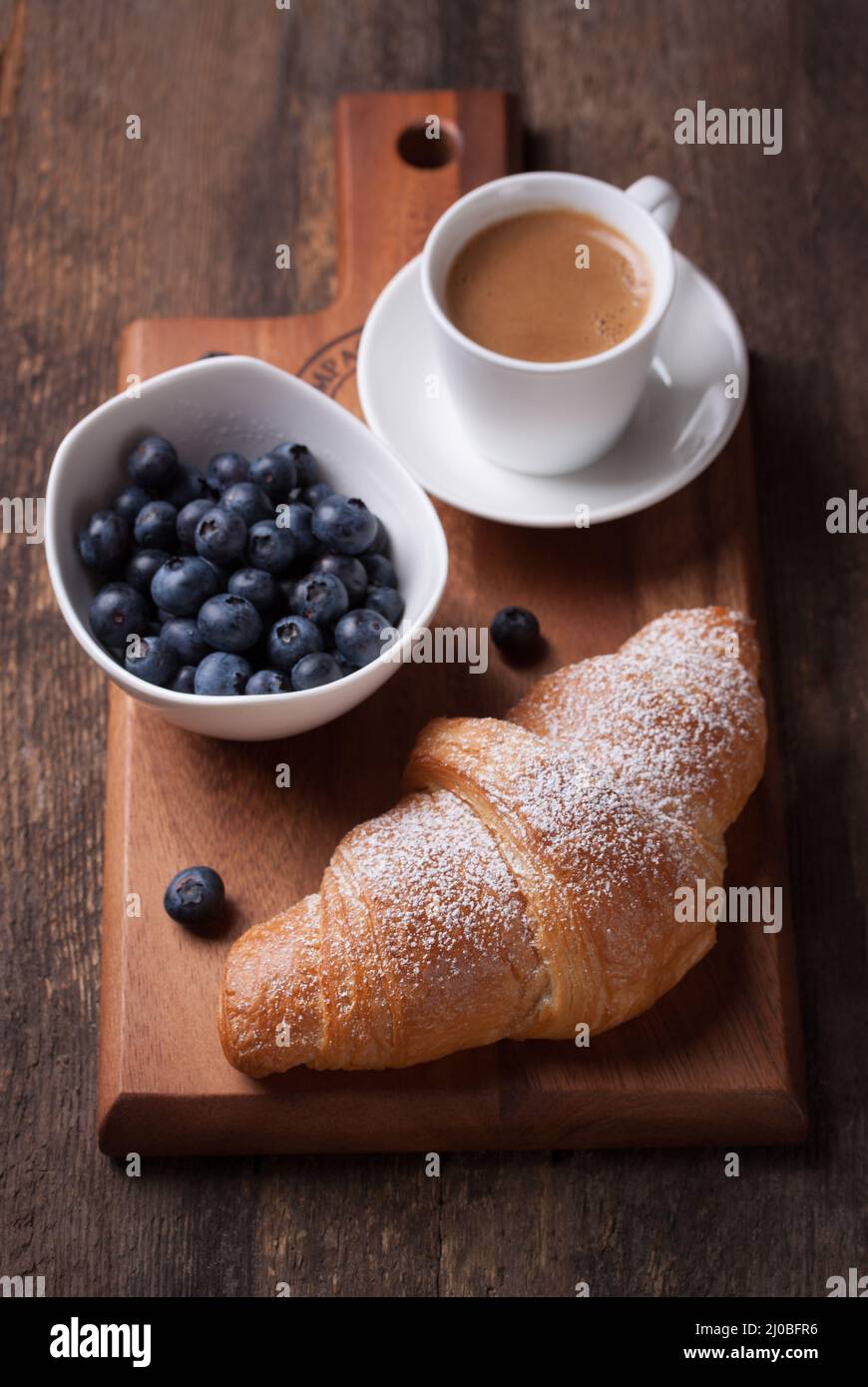 Roissant with coffee and blackberries on a wooden board. Selective ...