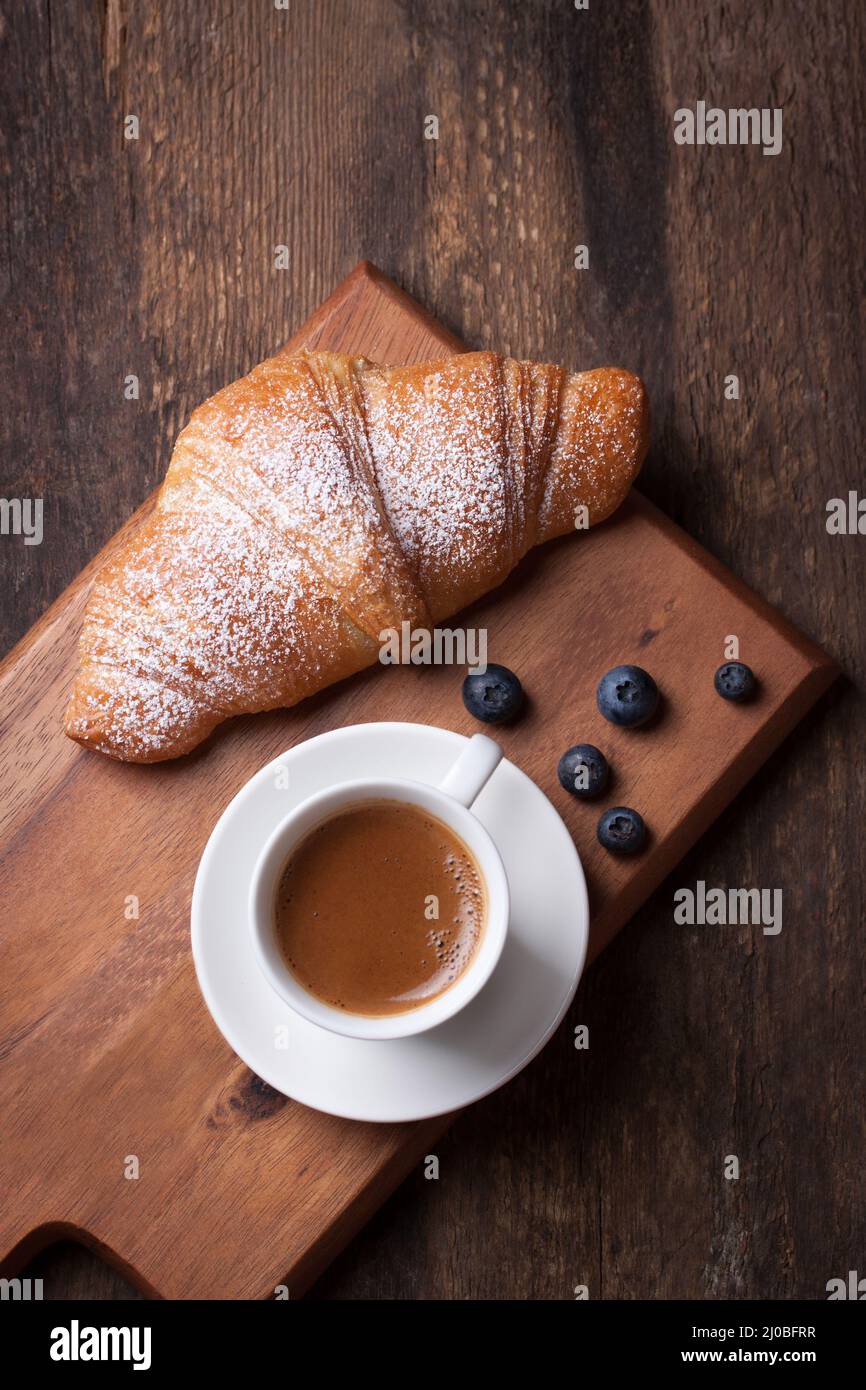 Croissant with coffee and blackberries on a wooden board. Selective ...