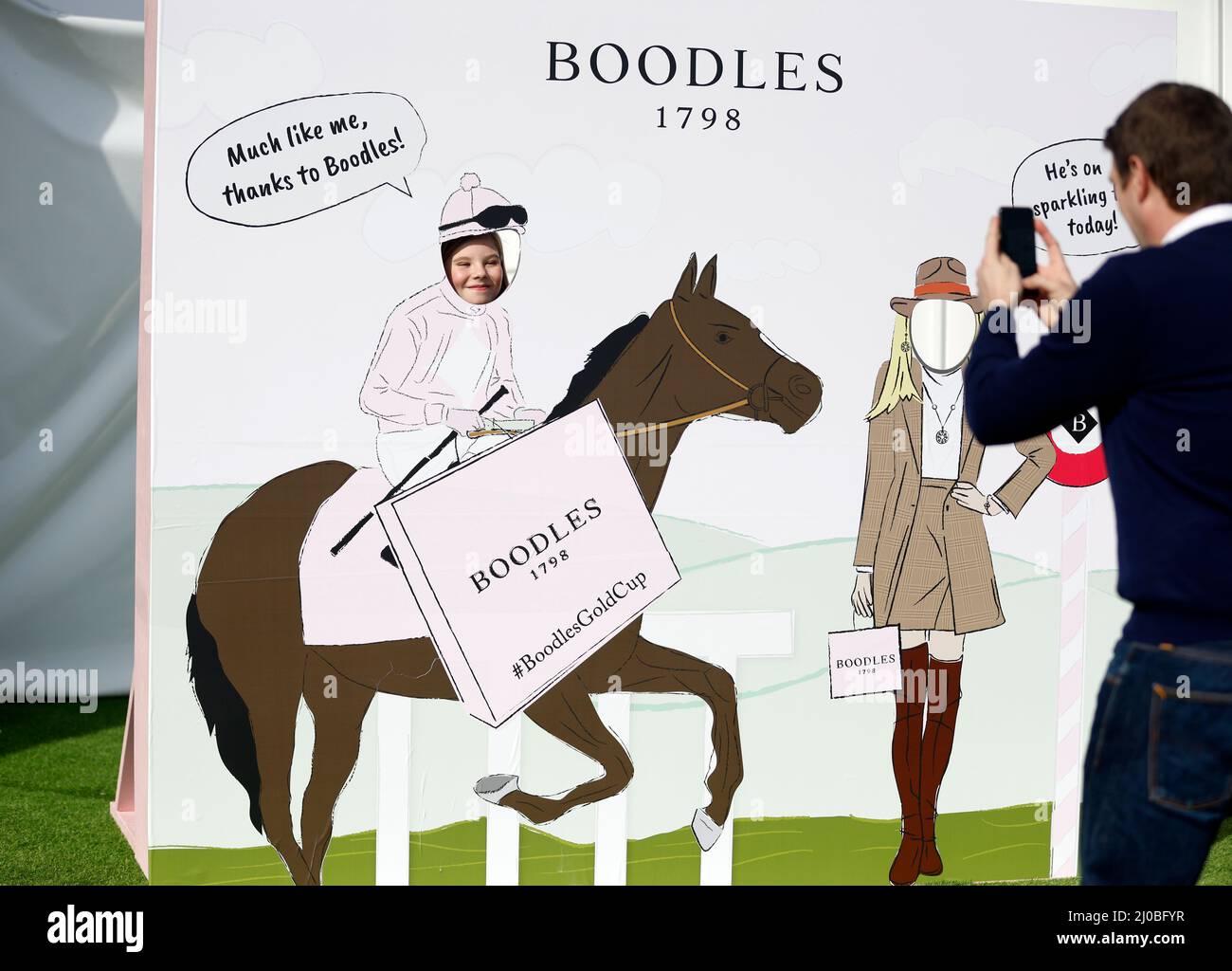 Spectators put their heads in a Boodles face in the hole board during ...