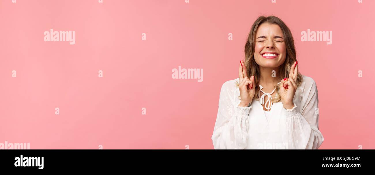 Portrait of excited hopeful blond girl making wish crossed fingers for ...
