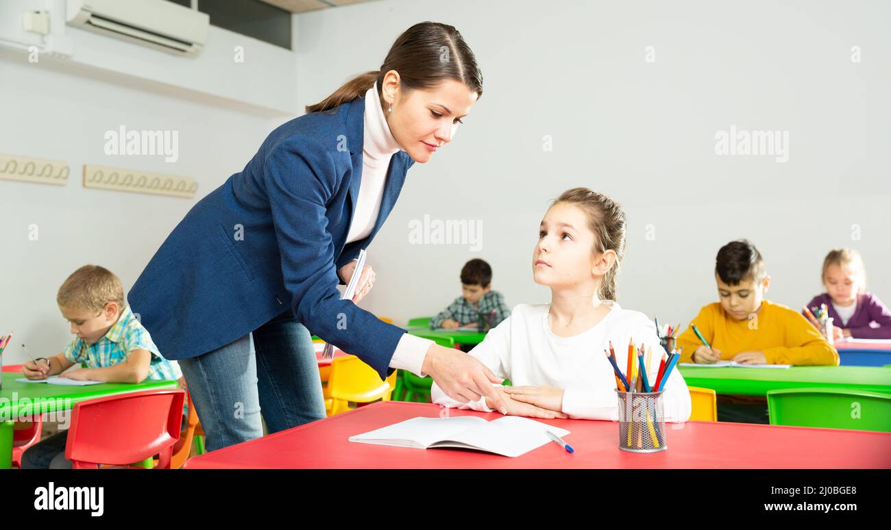 Female teacher helps schoolgirl complete an assignment in an elementary ...