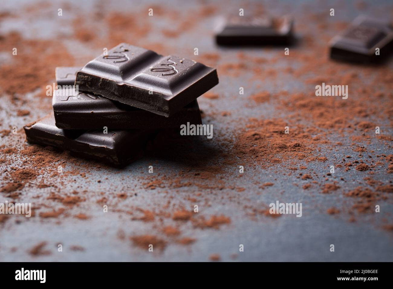 Dark chocolate stack with cocoa powder on a stone background with copy ...