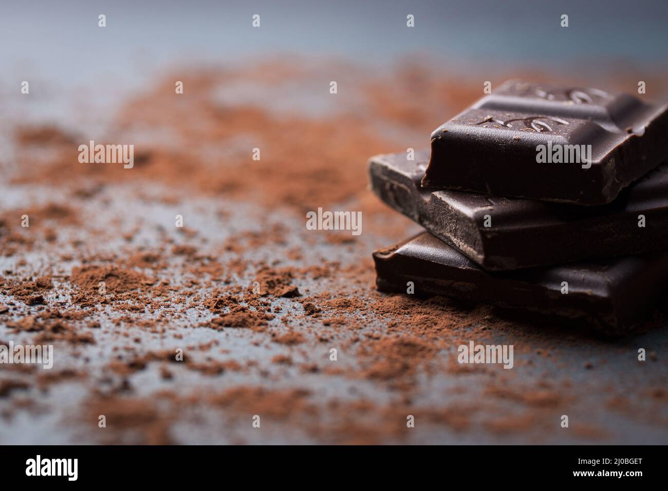 Dark chocolate stack with cocoa powder on a stone background with copy ...