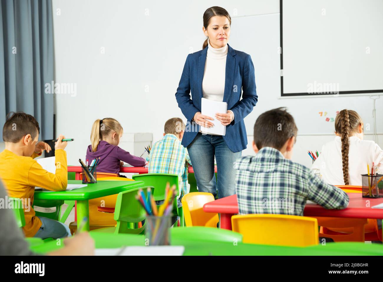 Teacher controlling work of school children Stock Photo - Alamy