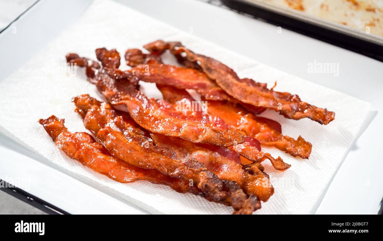 Step by step. Cooked bacon strips on a white tray with a paper towel ...