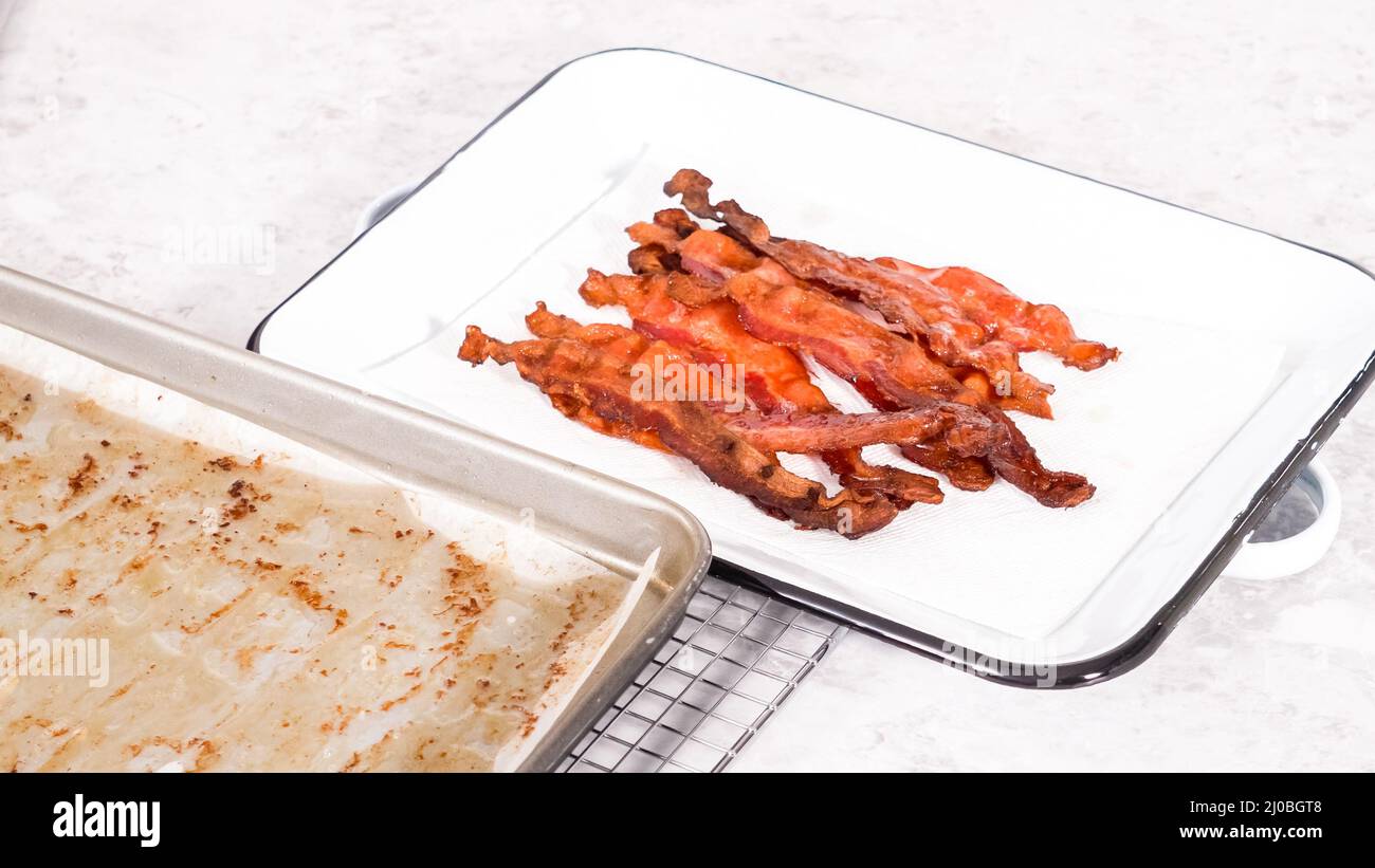 Step by step. Cooked bacon strips on a white tray with a paper towel ...
