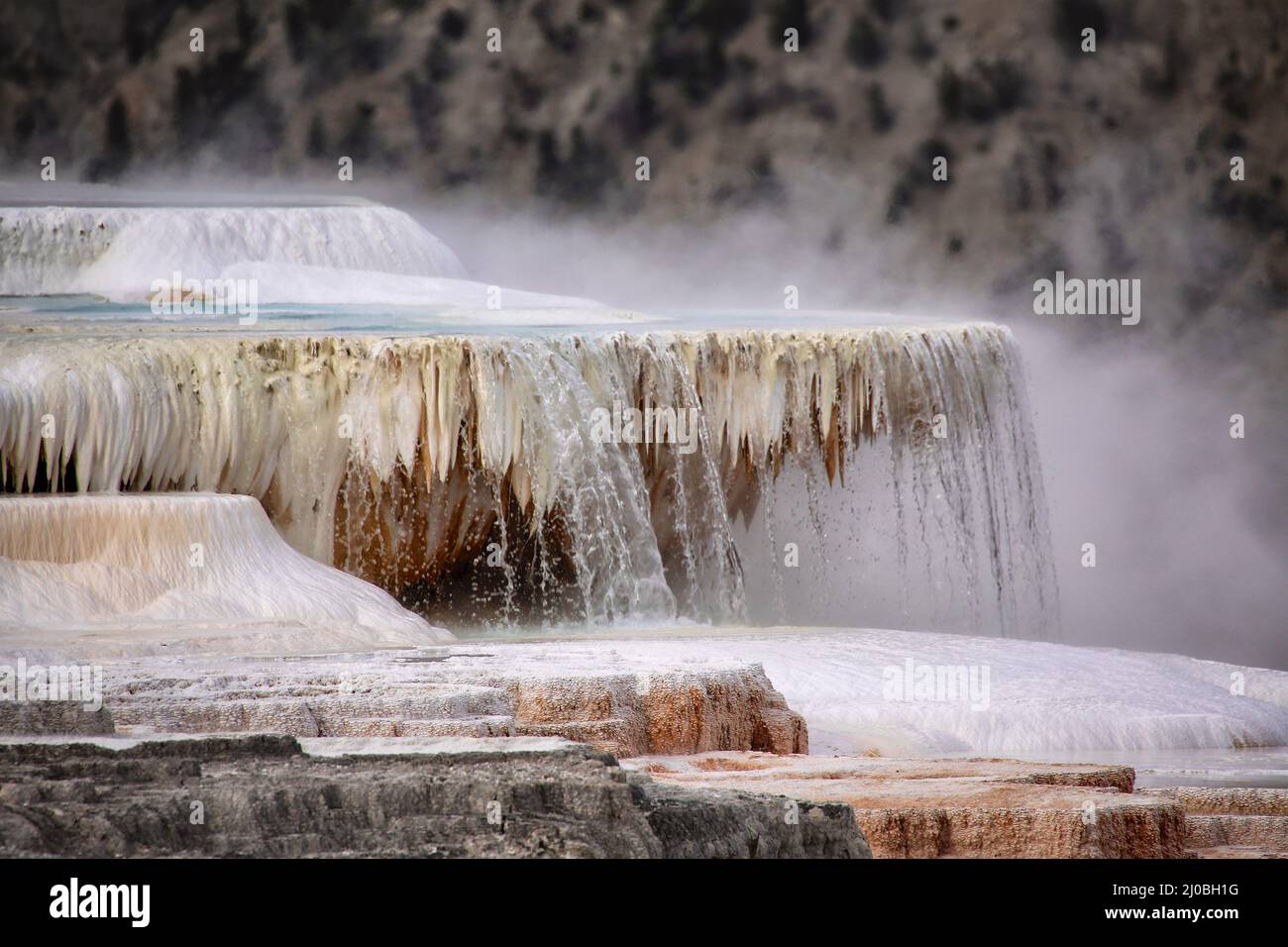 Water pours over a deposited limestone terrace at Mammoth Hot Springs ...