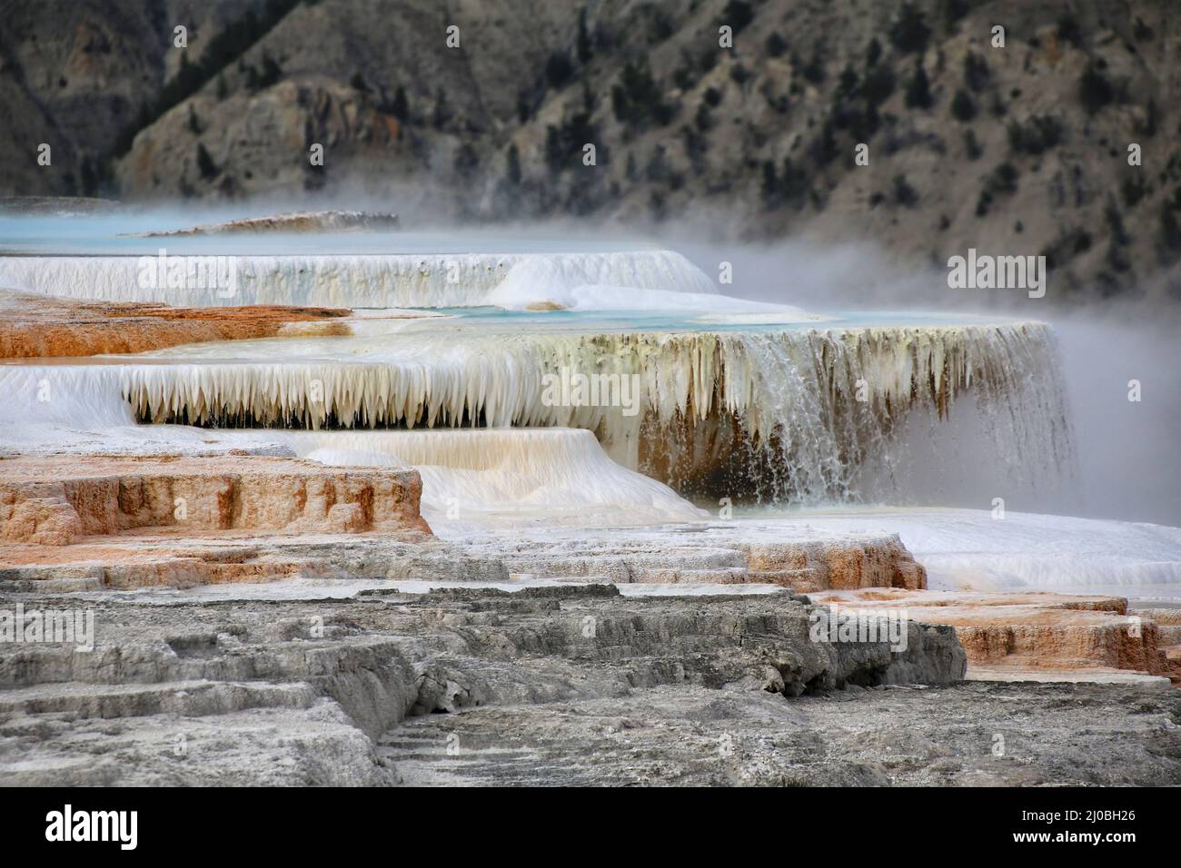 Water pours over a deposited limestone terrace at Mammoth Hot Springs ...