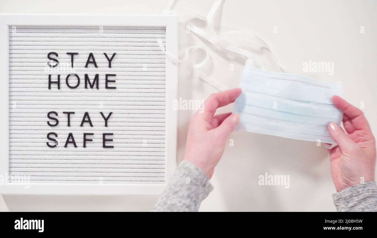 Flat lay. STAY HOME and STAY SAFE sign on message board with a blue ...