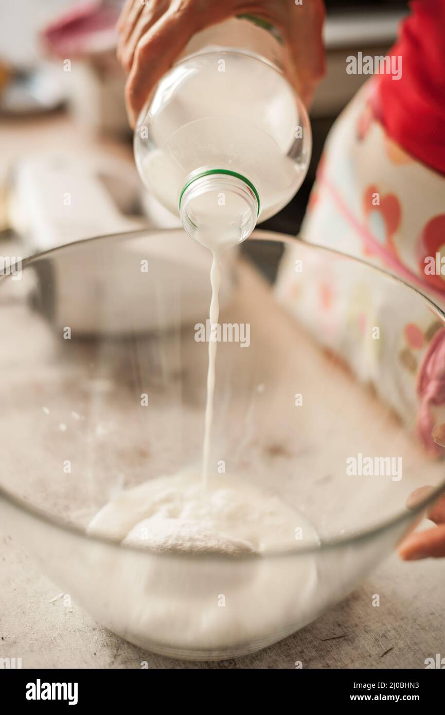 Woman pouring milk into glass bowl and making whipped cream. Close up ...