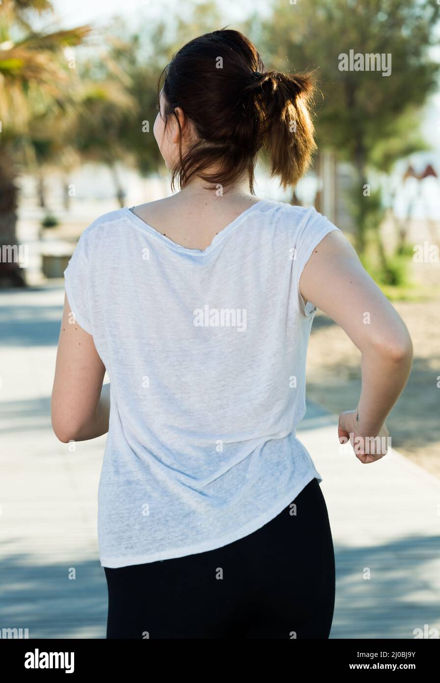 Female 20-30 years old is jogging her back in black T-shirt Stock Photo ...