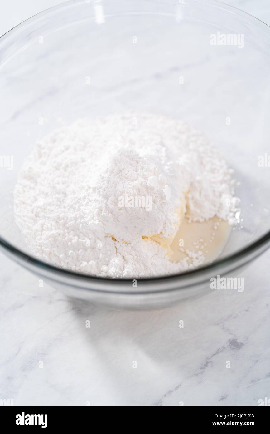 Mixing ingredients in a large glass mixing bowl to make the cream ...