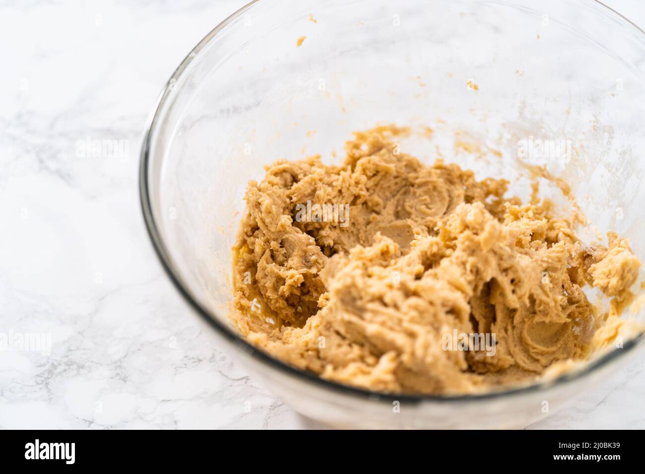 Mixing ingredients with a hand mixer to bake eggnog cookies with a ...