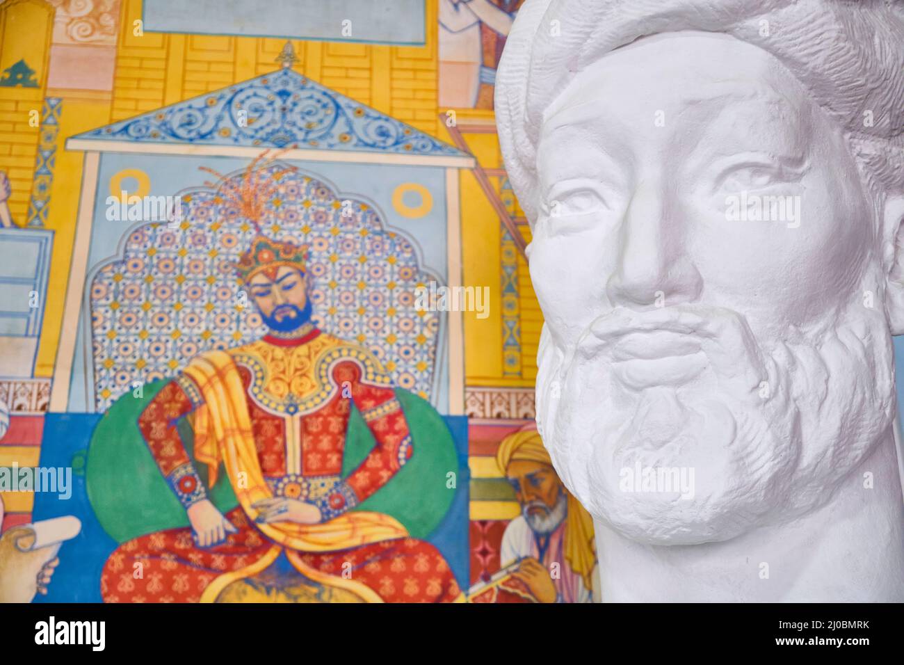 A white bust sculpture of Alisher Navoi in front of a colorful painting ...