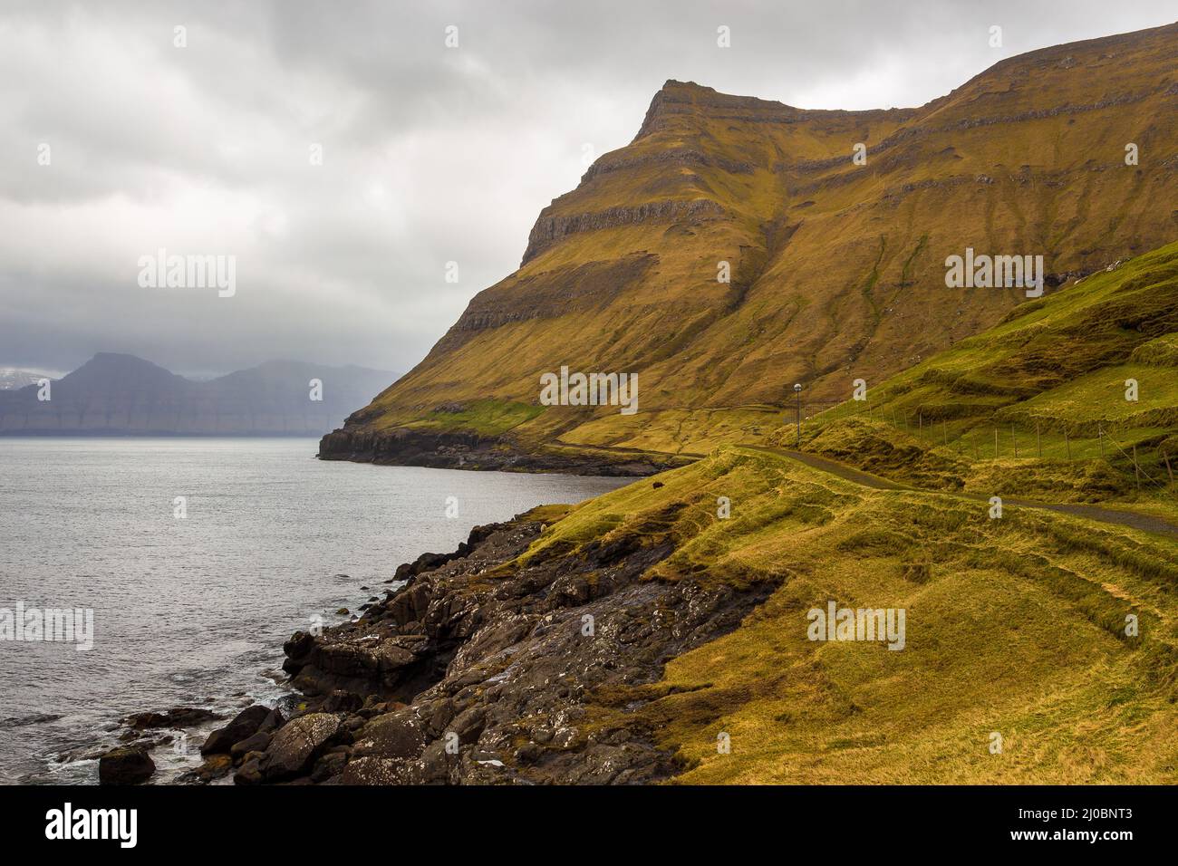 Steep shore, mountain landscape on the island of Eysturoy. Cloudy ...