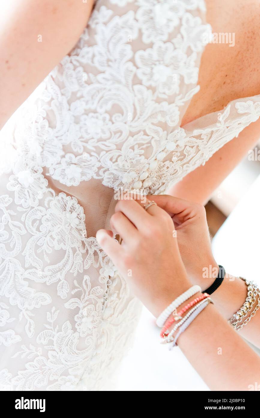 March 2022, hands fasten the dress of the bride photographed from the ...
