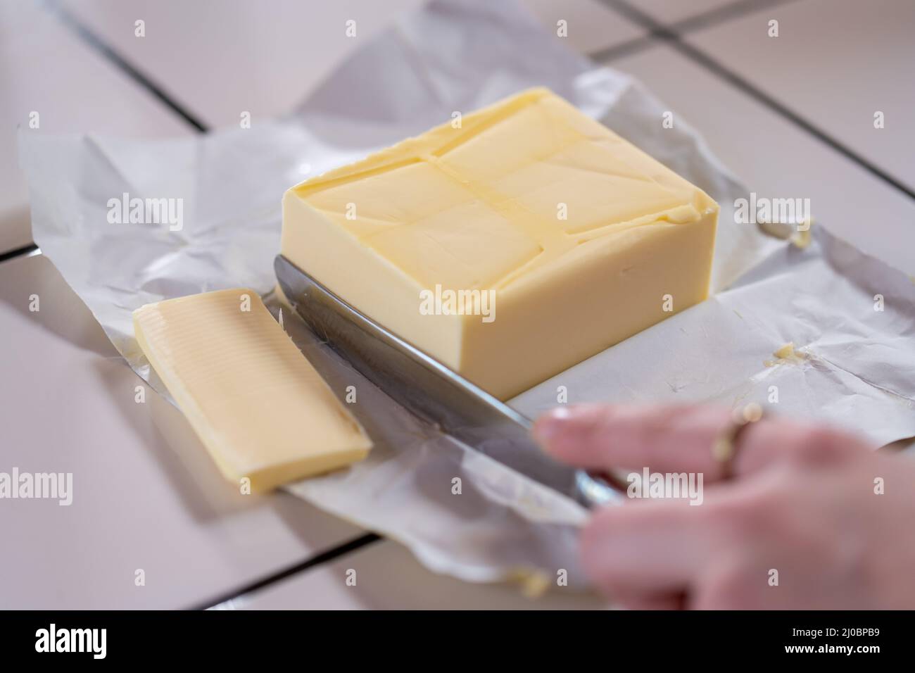 Cutting a slice of butter in a kitchen. Close-up Stock Photo - Alamy