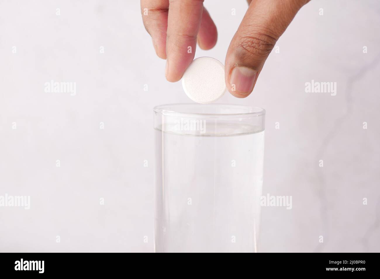 Effervescent soluble tablet pills and glass of water on purple ...