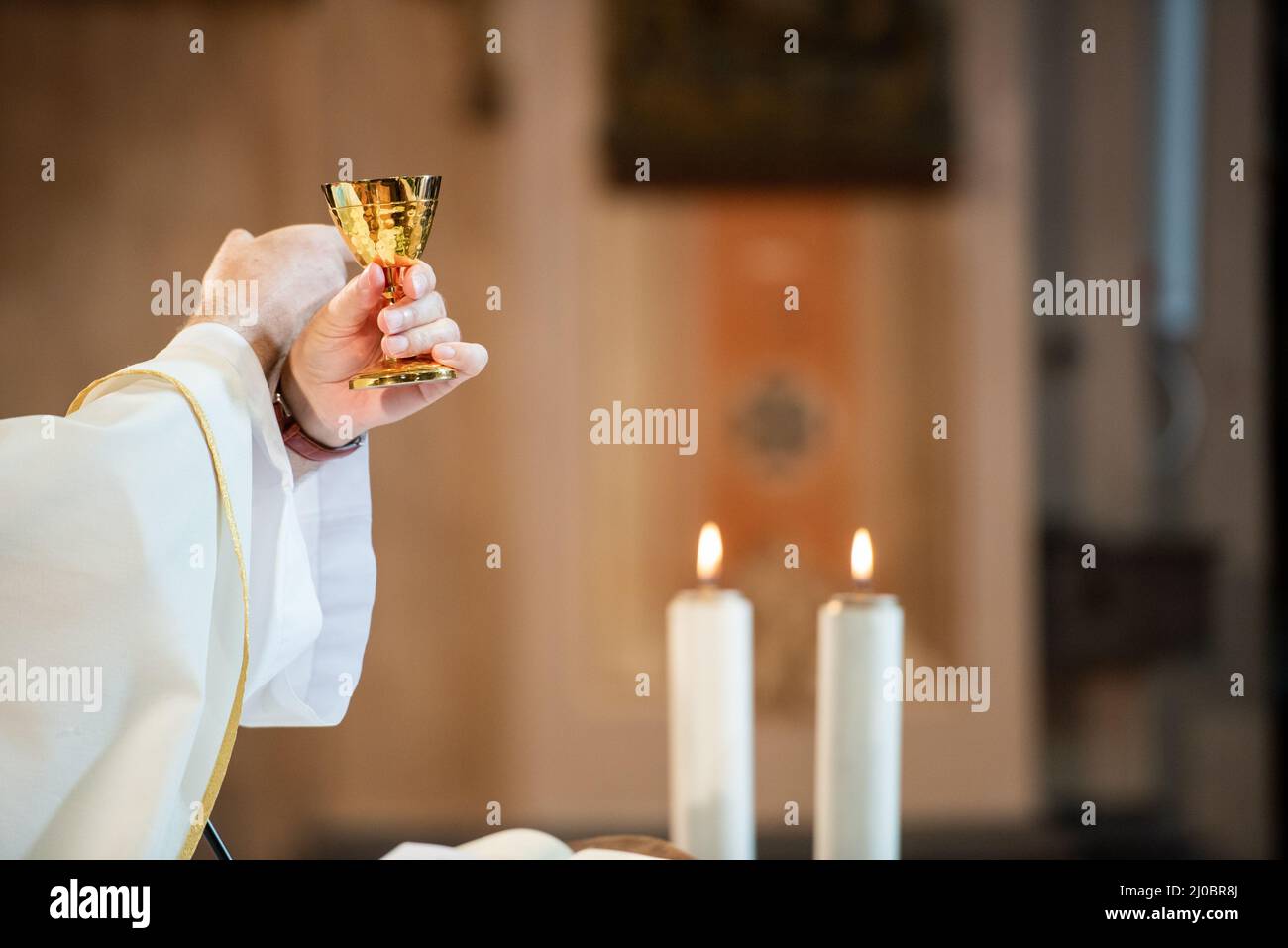 March 2022, Hands of a priest raise a chalice for the Eucharistic ...