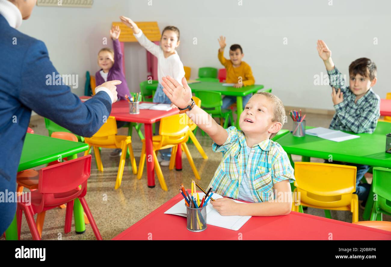Happy schoolchildren with hands raised during lesson Stock Photo - Alamy Happy schoolchildren with hands raised during lesson Stock Photo - Alamy