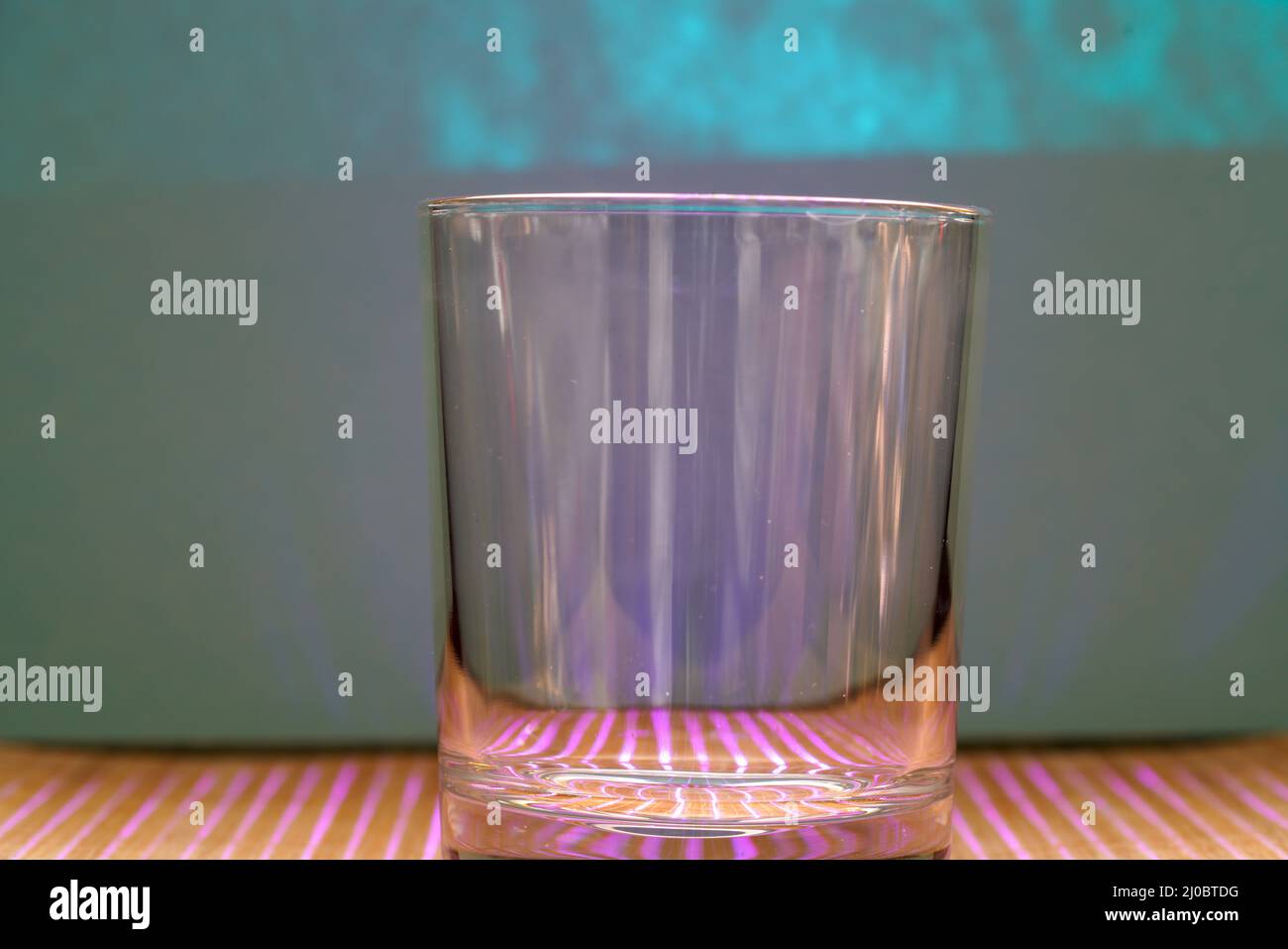 Selective focus of an empty glass cup with pink stripes on the table ...