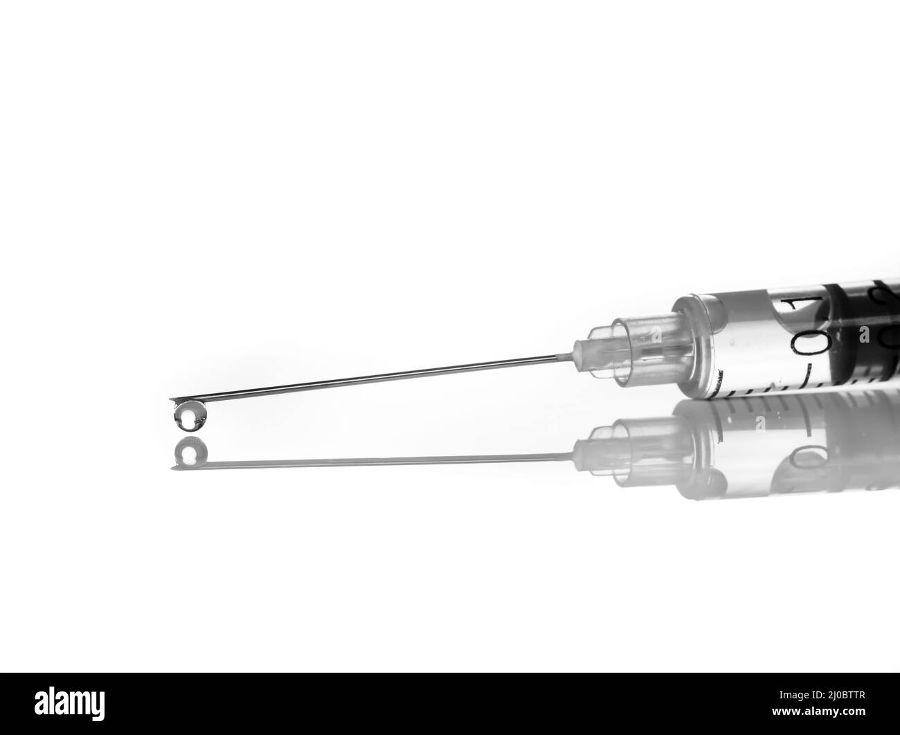 syringe with a needle and a drop of water at the end of the needle on a ...