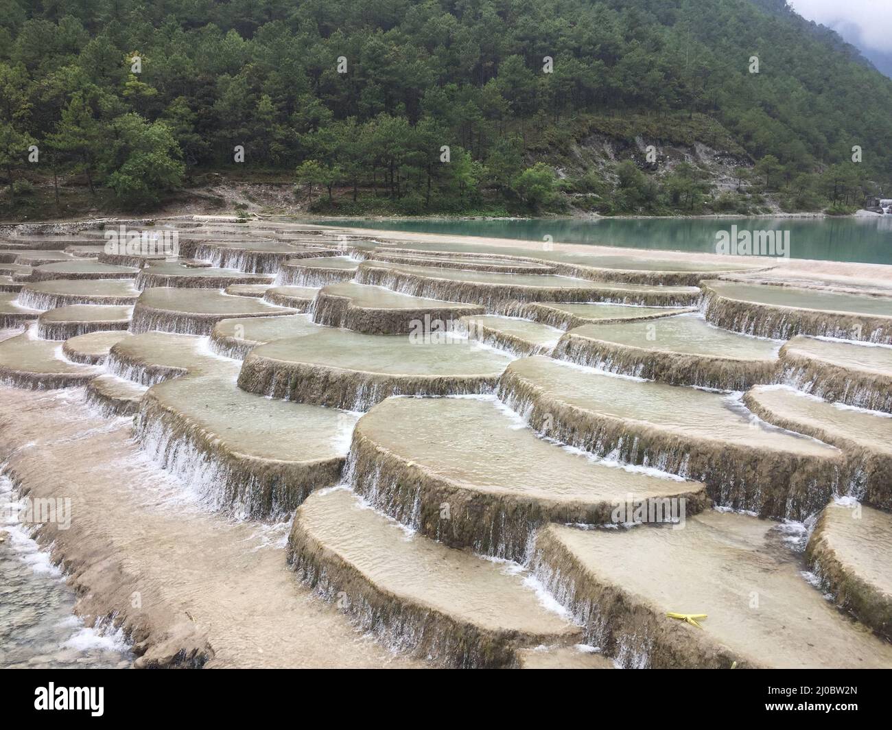 Waterfall of Baishui river at Blue Moon Valley in background of Jade Dragon snow mountain Stock ...
