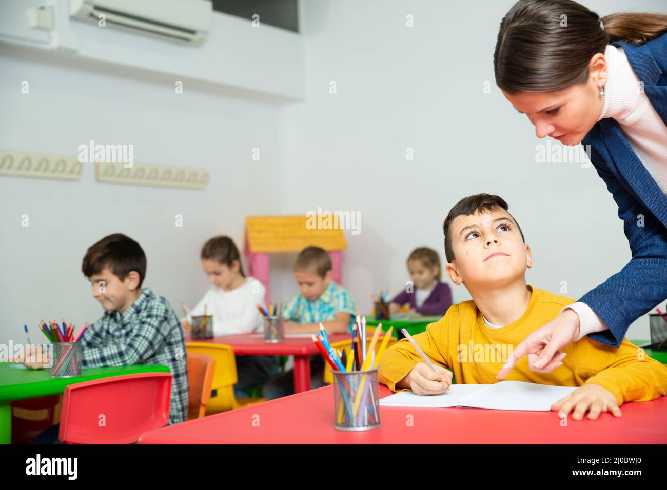 Teacher woman helping children during lesson Stock Photo - Alamy