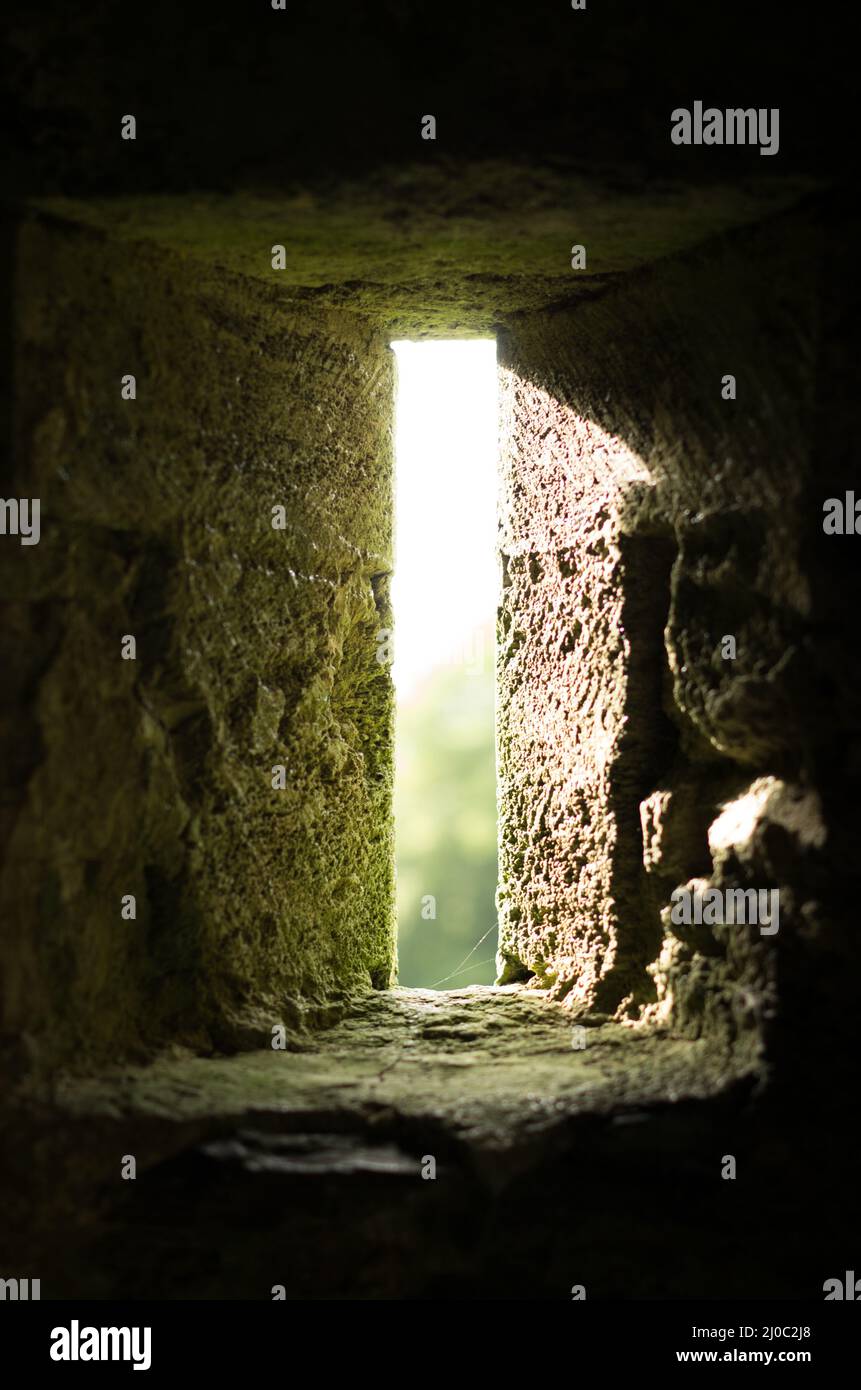 Sunlight shining through a slit window in a ruined historical building ...