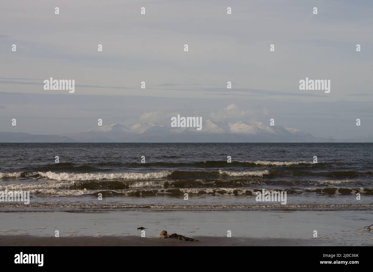 Waves breaking on the beach at Ayr with the snow capped peaks of the ...