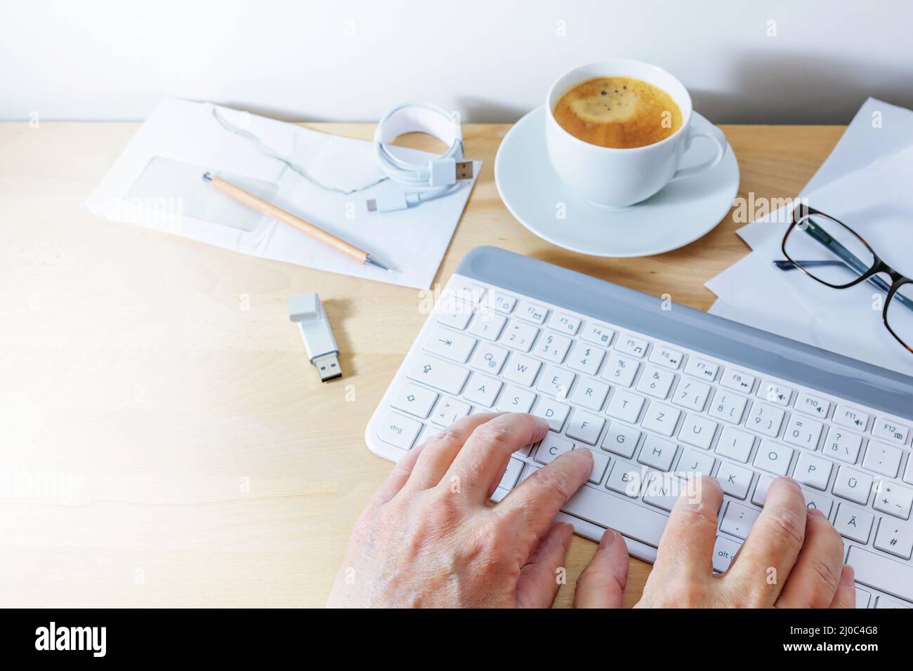 Hands using a computer keyboard on an office desk with coffee, usb ...