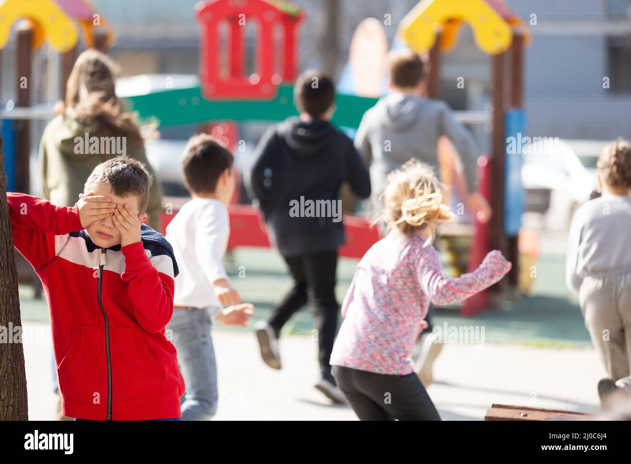 Boy playing hide and seek with friends Stock Photo - Alamy